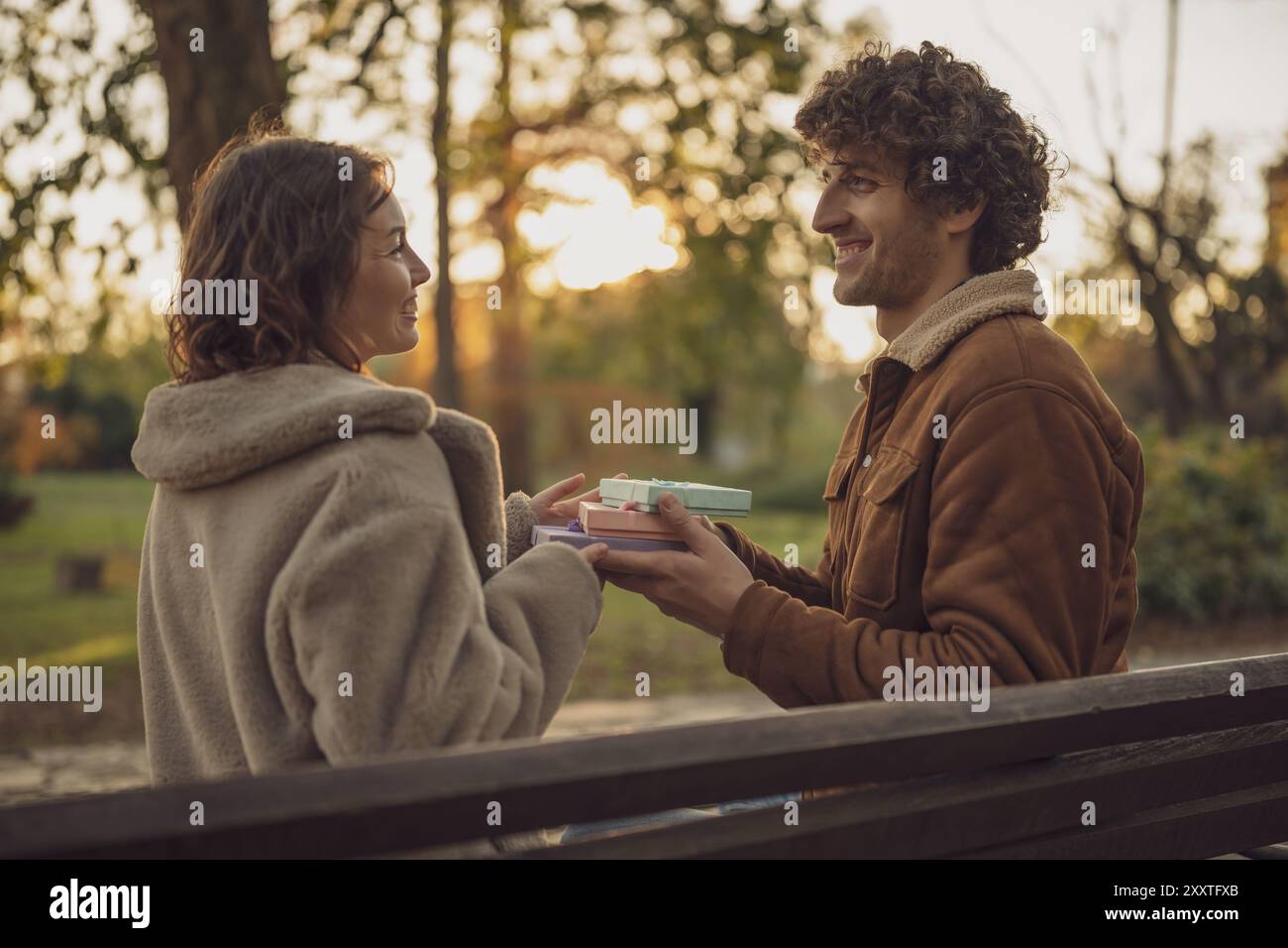 Happy loving couple enjoying their time together in park. Man is giving ...