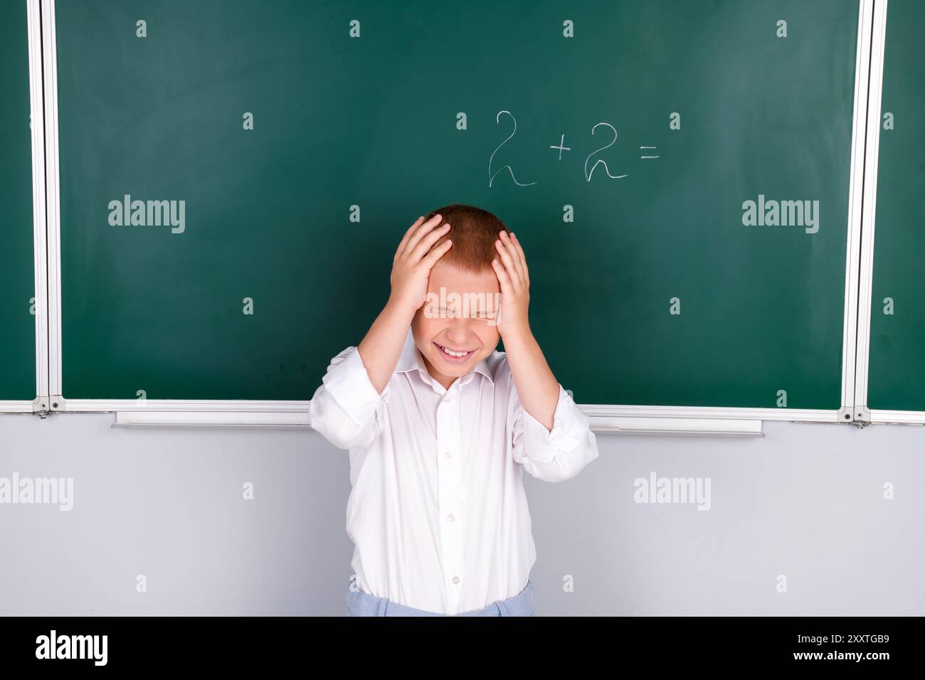Photo of funny sad upset adorable boy standing in class room solve math ...