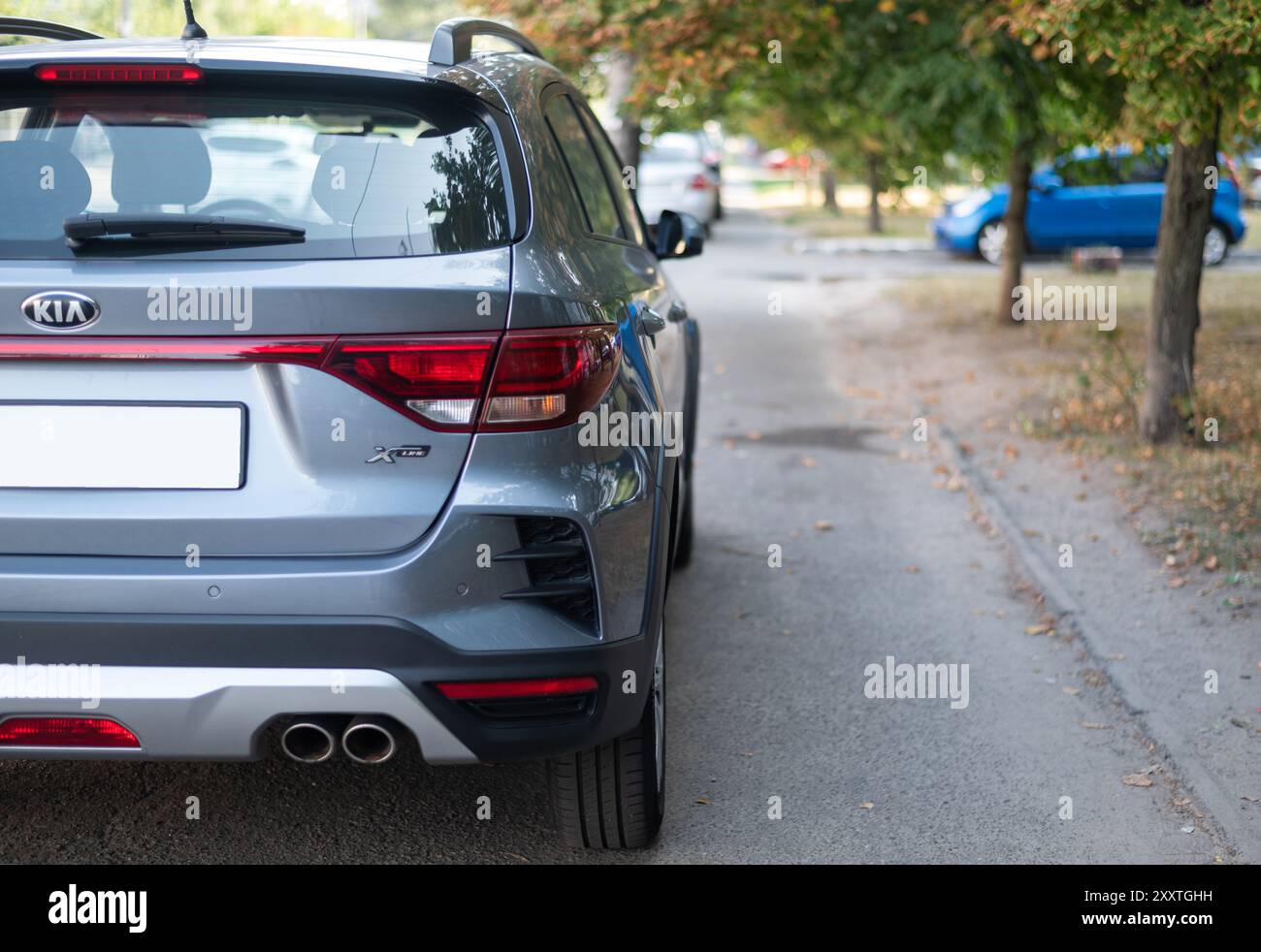 Rear view of a parked grey Kia SUV on a quiet suburban street ...
