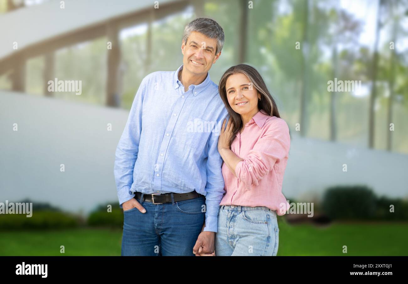 Happy couple smiling together at modern building during sunny weather ...