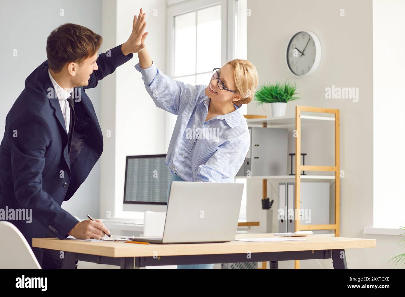 Two joyful colleagues giving high five in modern office, celebrating ...