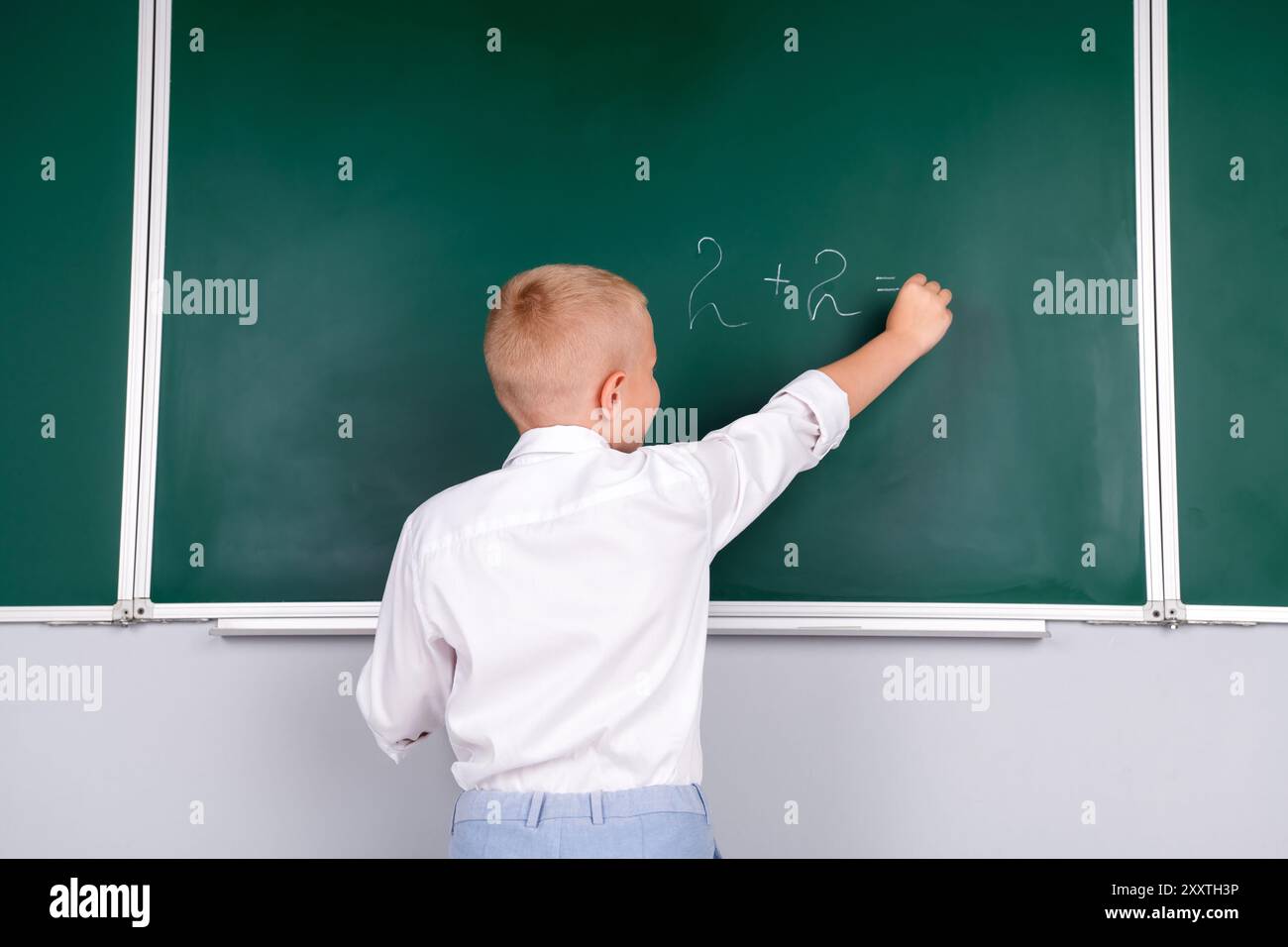 Photo of clever adorable boy standing in class room solve math task ...