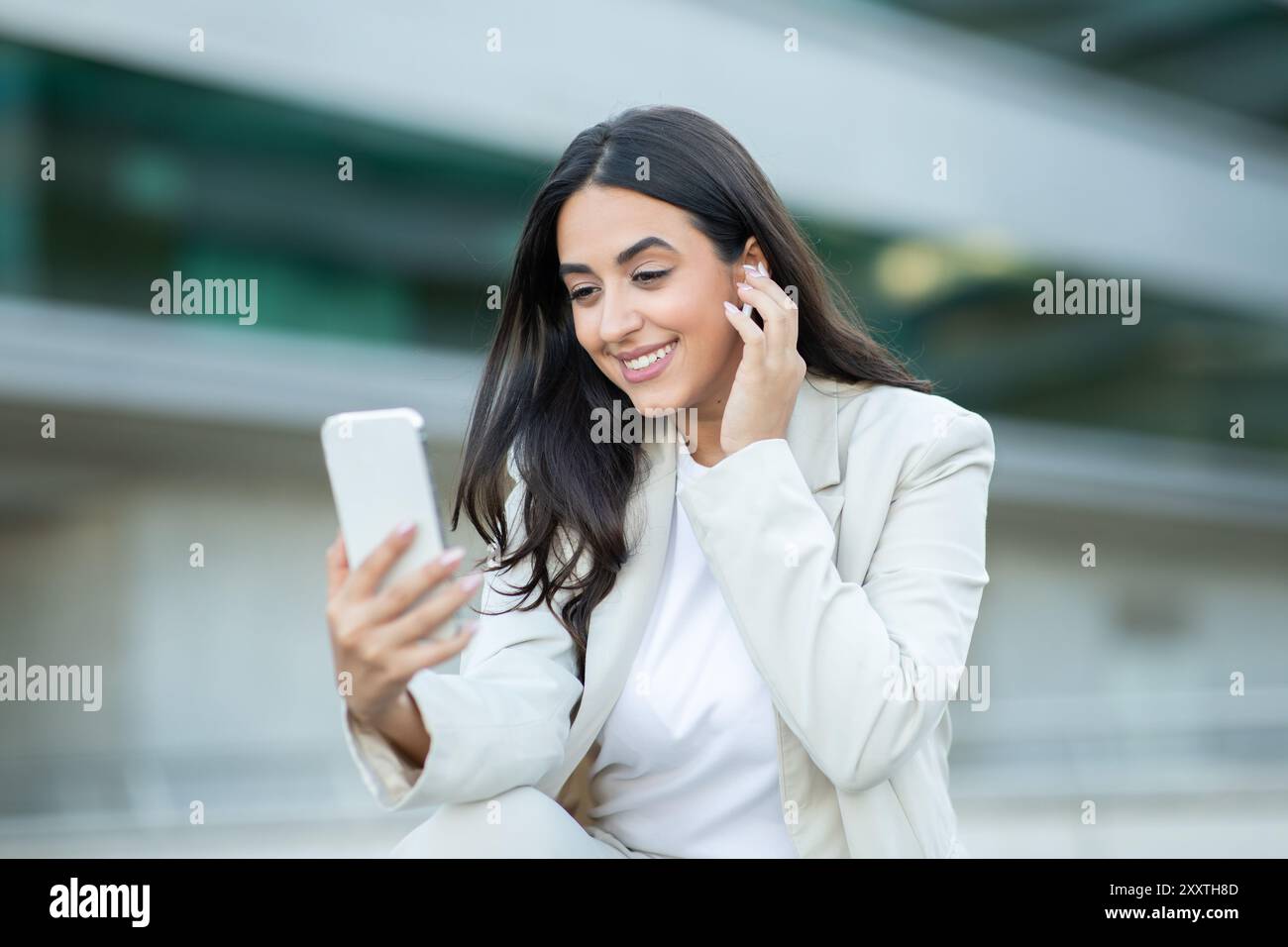 Young woman smiles while using smartphone in urban setting Stock Photo ...