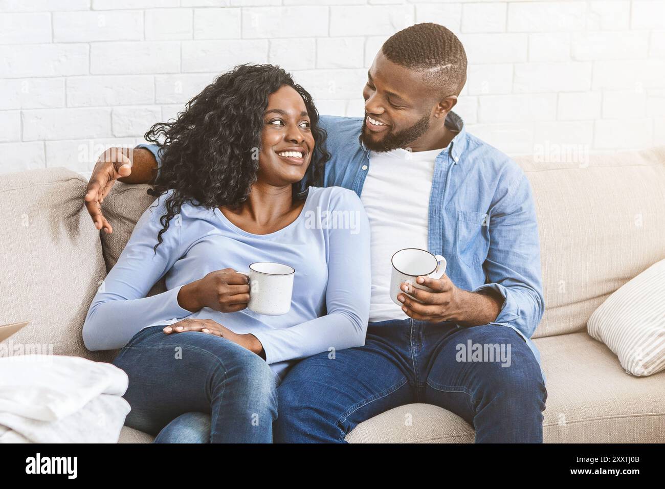 Black couple in love sitting on sofa at new house Stock Photo - Alamy