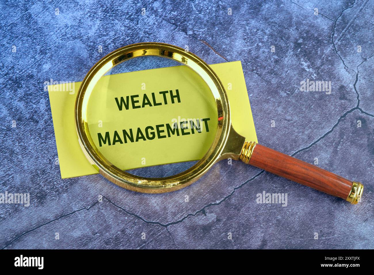WEALTH MANAGEMENT words written through a magnifying glass on a yellow ...