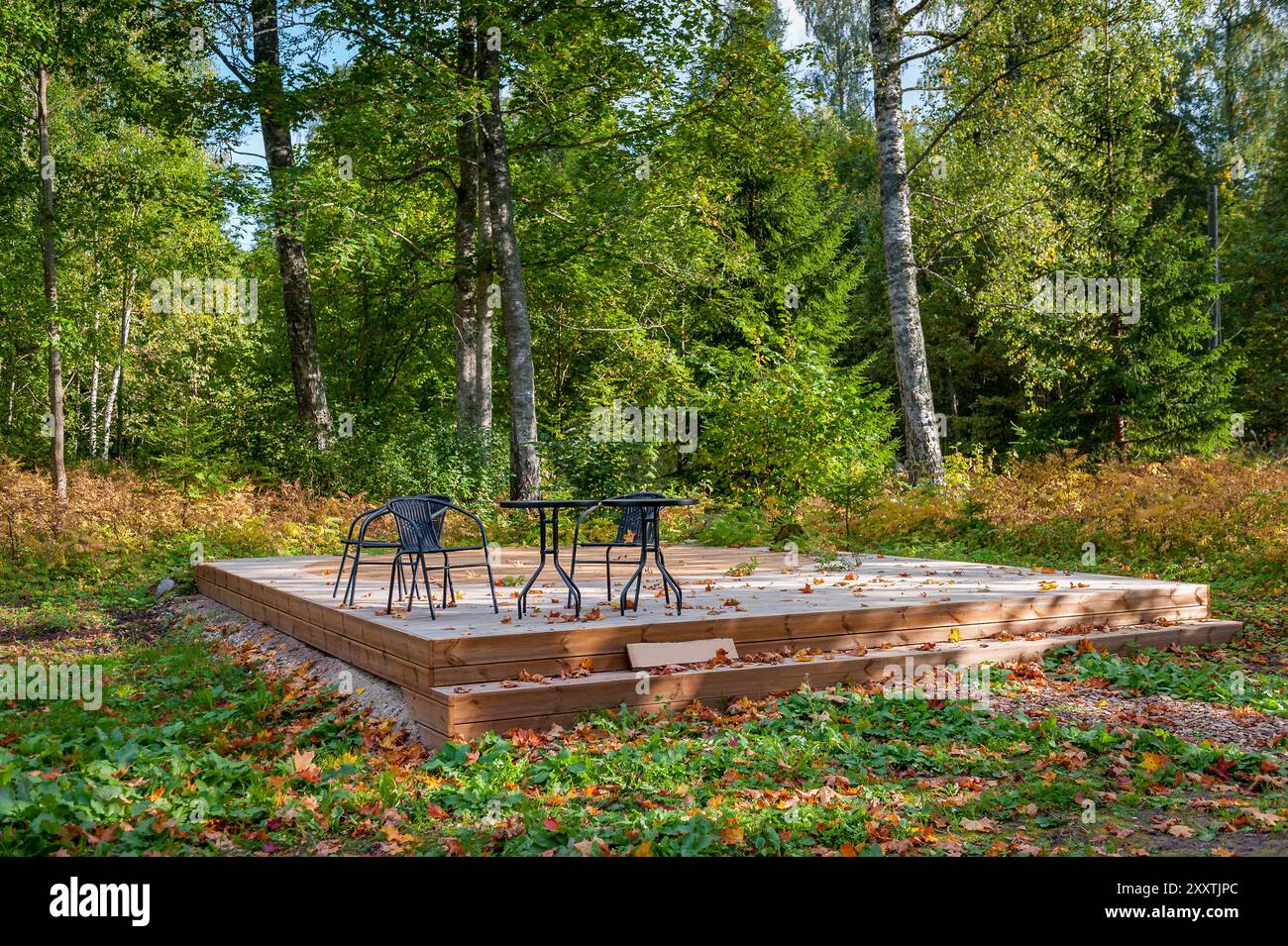 Wooden glamping deck with table and chairs in an autumn forest ...