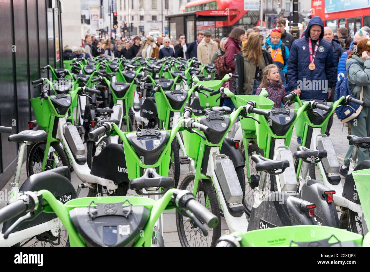 pedestrian walk past masses of rental Lime e-bikes on pavement near ...