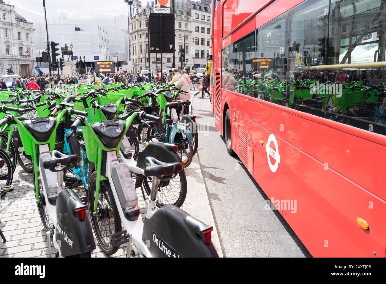 pedestrian walk past masses of rental Lime e-bikes on a road side near ...
