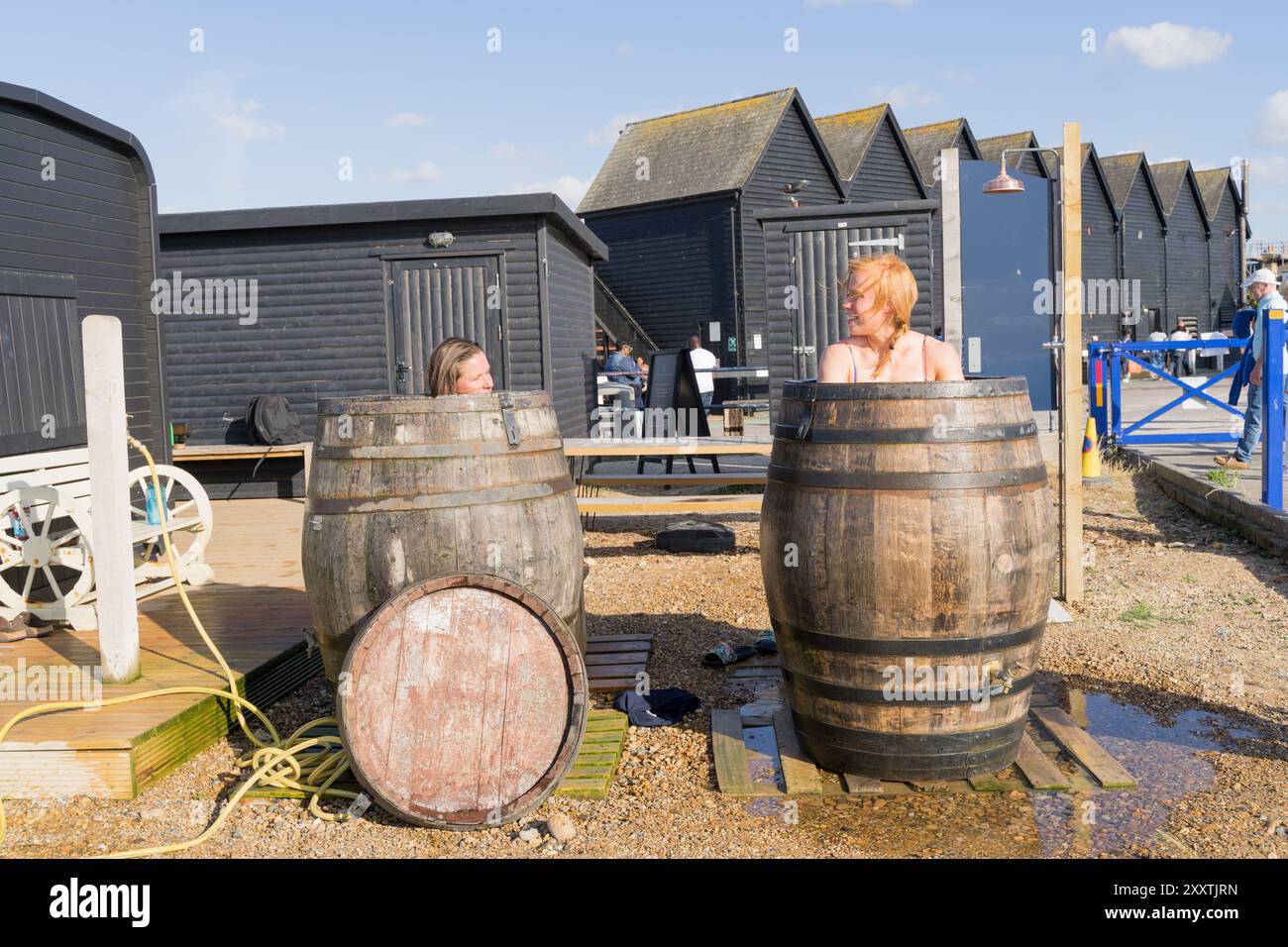 Two ladies dip into cold water barrels after a sauna in Margate beach ...