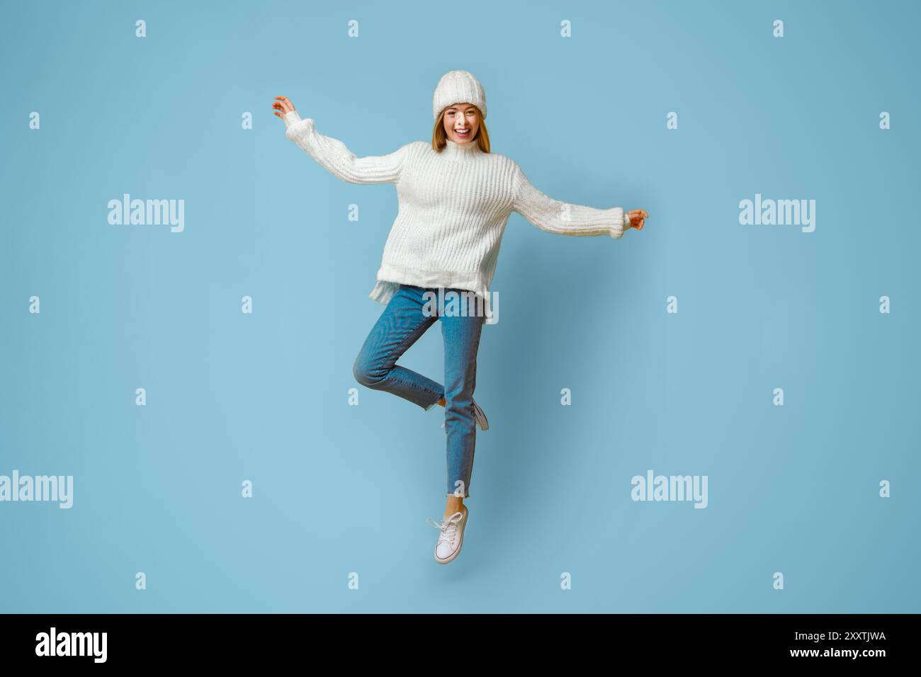 Laughing winter girl jumping on one leg Stock Photo - Alamy