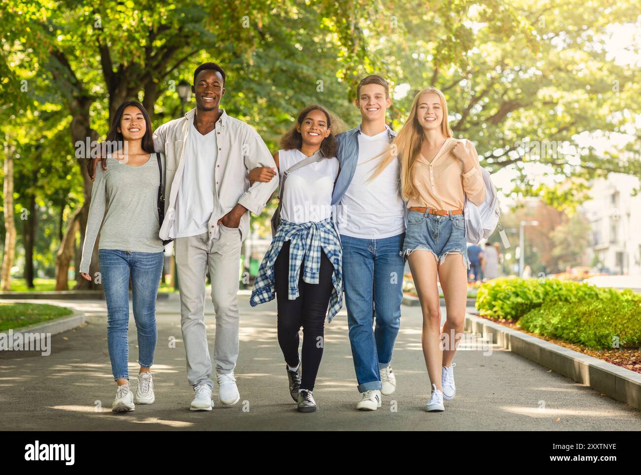 Carefree international students walking together in public park after ...