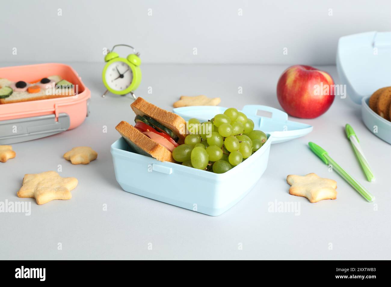 Lunch box with snacks, alarm clock and stationery on white table Stock ...