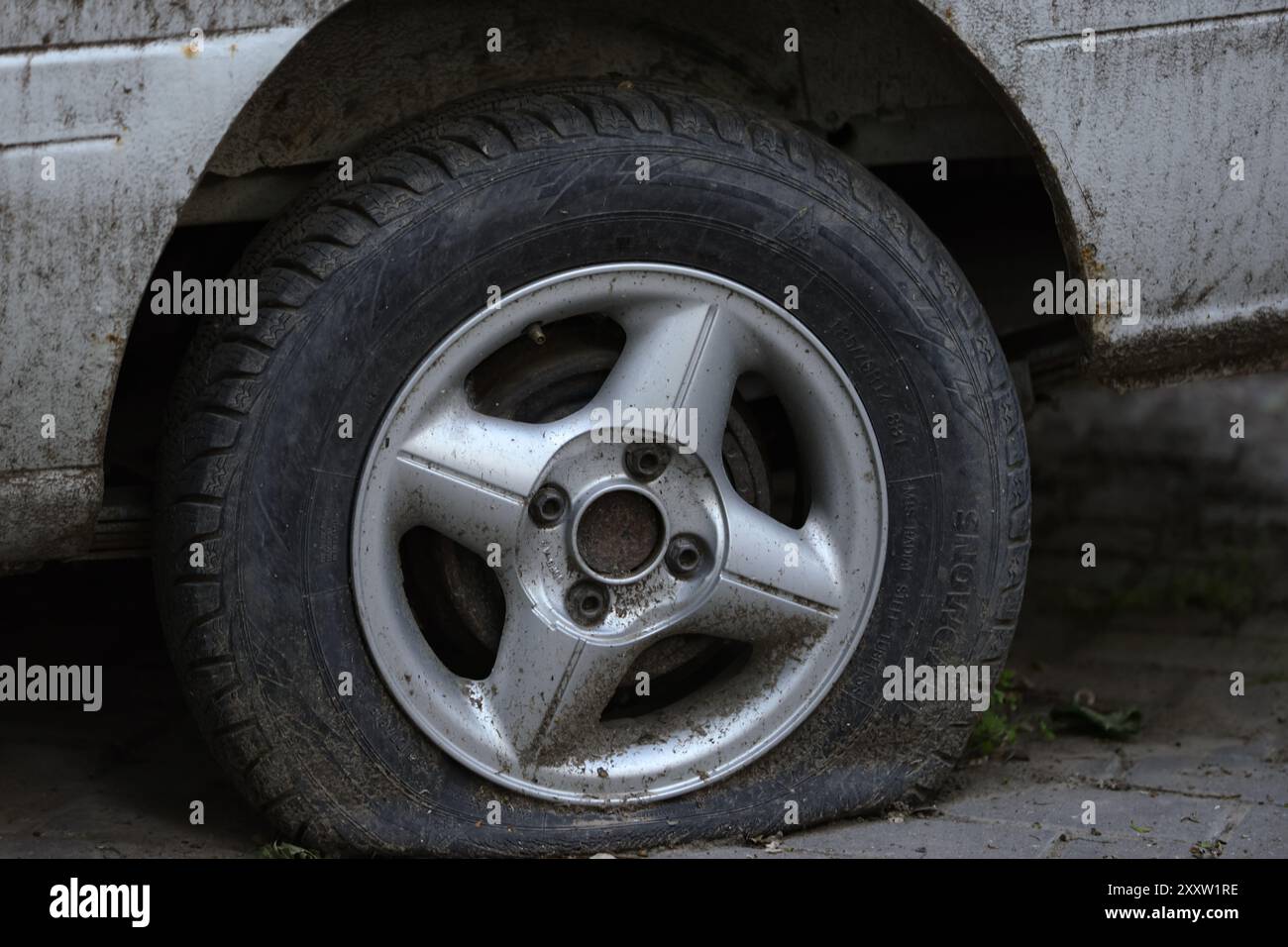 Dirty car wheel with a flat tire, showing signs of disuse. Close-up ...