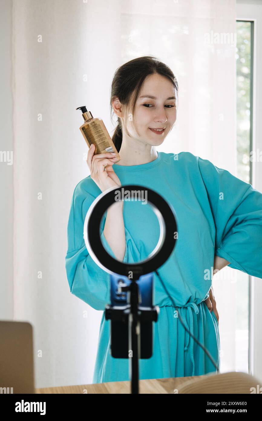 Beauty influencer demonstrating skincare product with ring light setup ...
