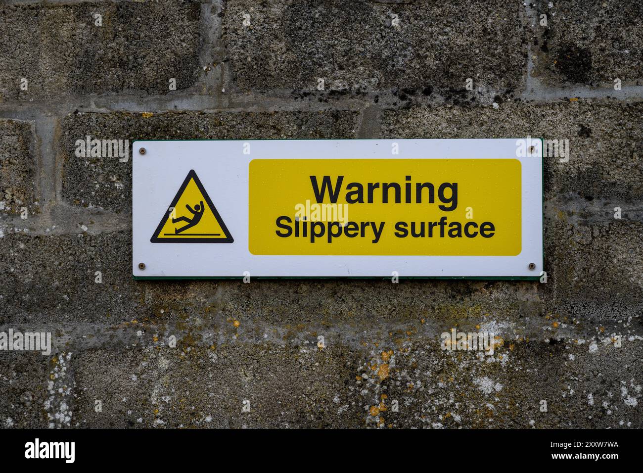 Yellow warning sign sayin slippery surface Stock Photo - Alamy