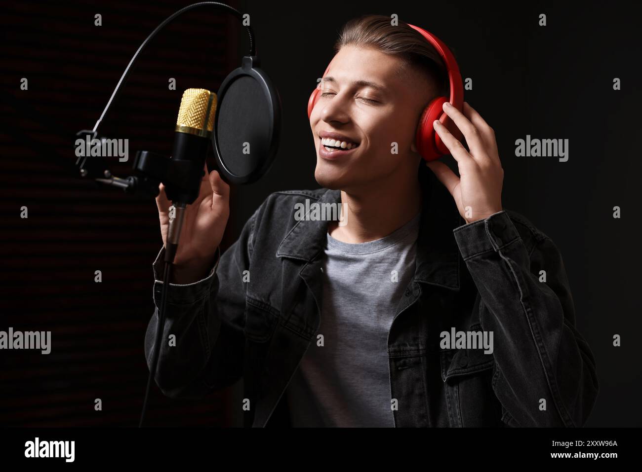 Man wearing headphones singing into microphone in professional record ...