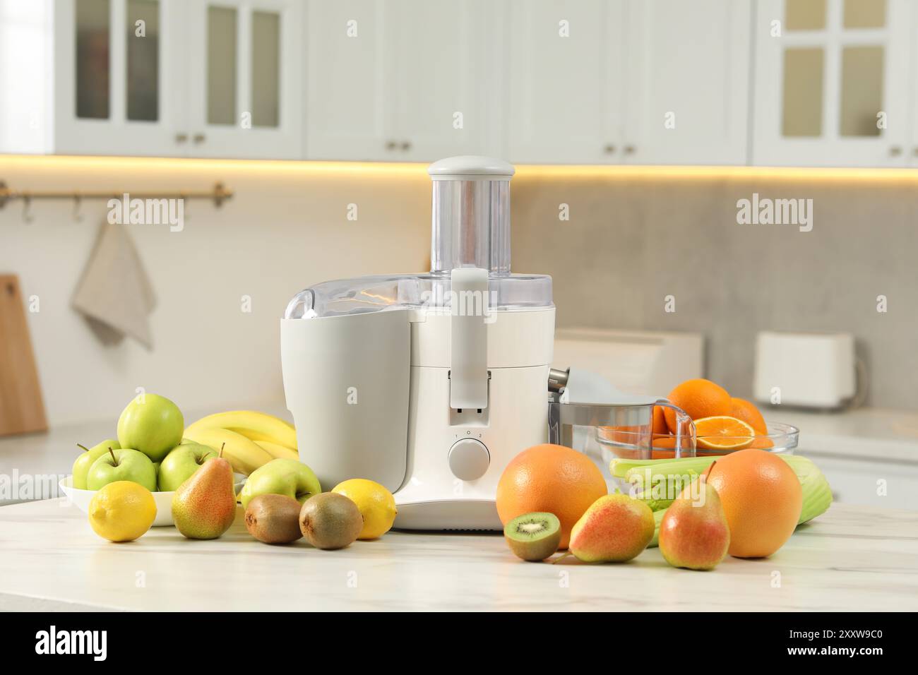 Modern juicer and fruits on white marble table in kitchen Stock Photo ...