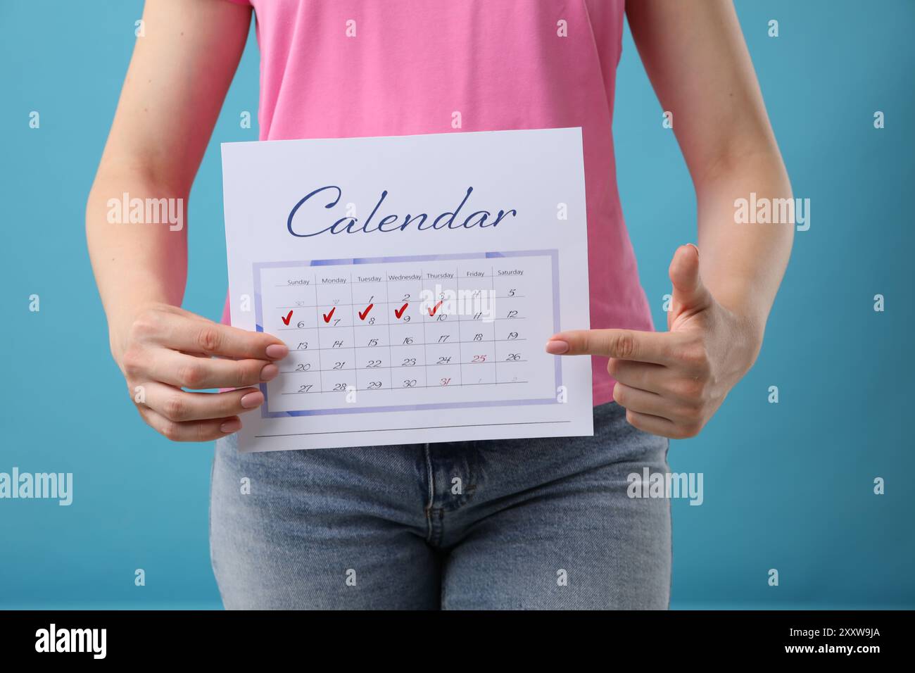 Woman holding calendar with marked menstrual cycle days on light blue ...