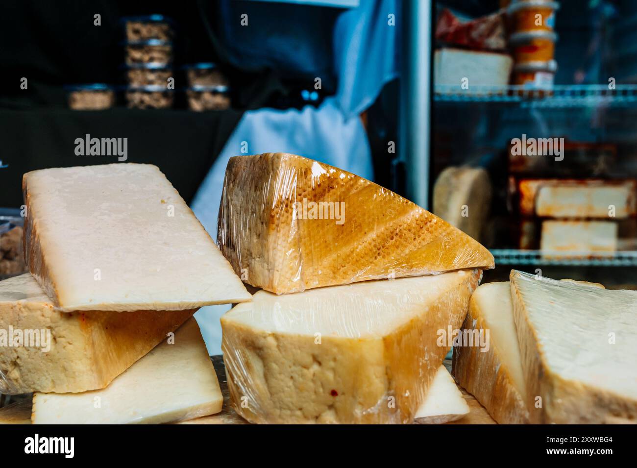 A stack of plastic-wrapped blocks of cheese on display in a grocery ...