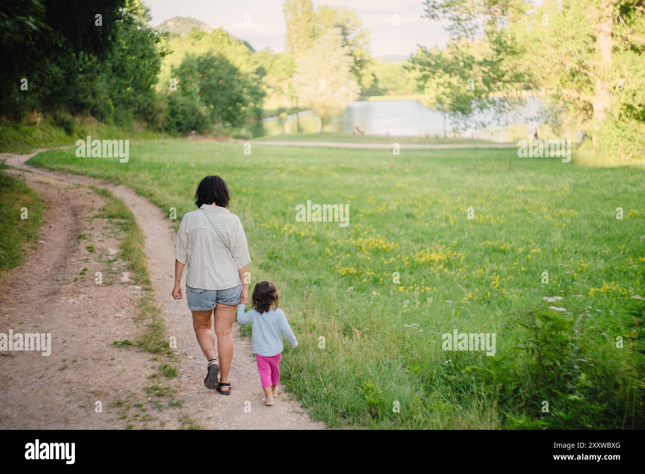 Mother and daughter walking together along path in nature hand in hand ...