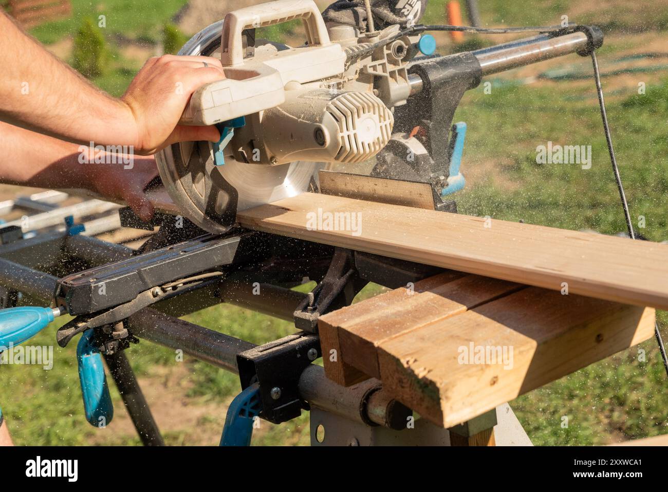 man cutting a wooden plank with a table saw (bench saw) to make a diy ...