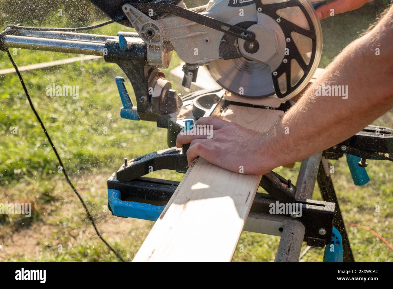 man cutting a wooden plank with a table saw (bench saw) to make a diy ...