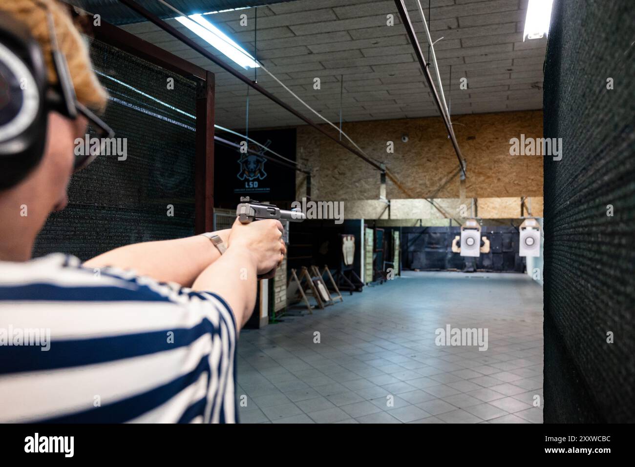 woman aims at a target with a pistol at a shooting range Stock Photo ...