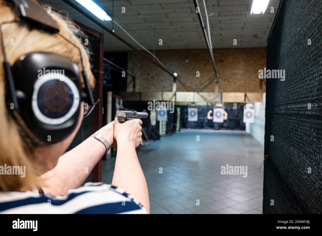 woman aims at a target with a pistol at a shooting range Stock Photo ...