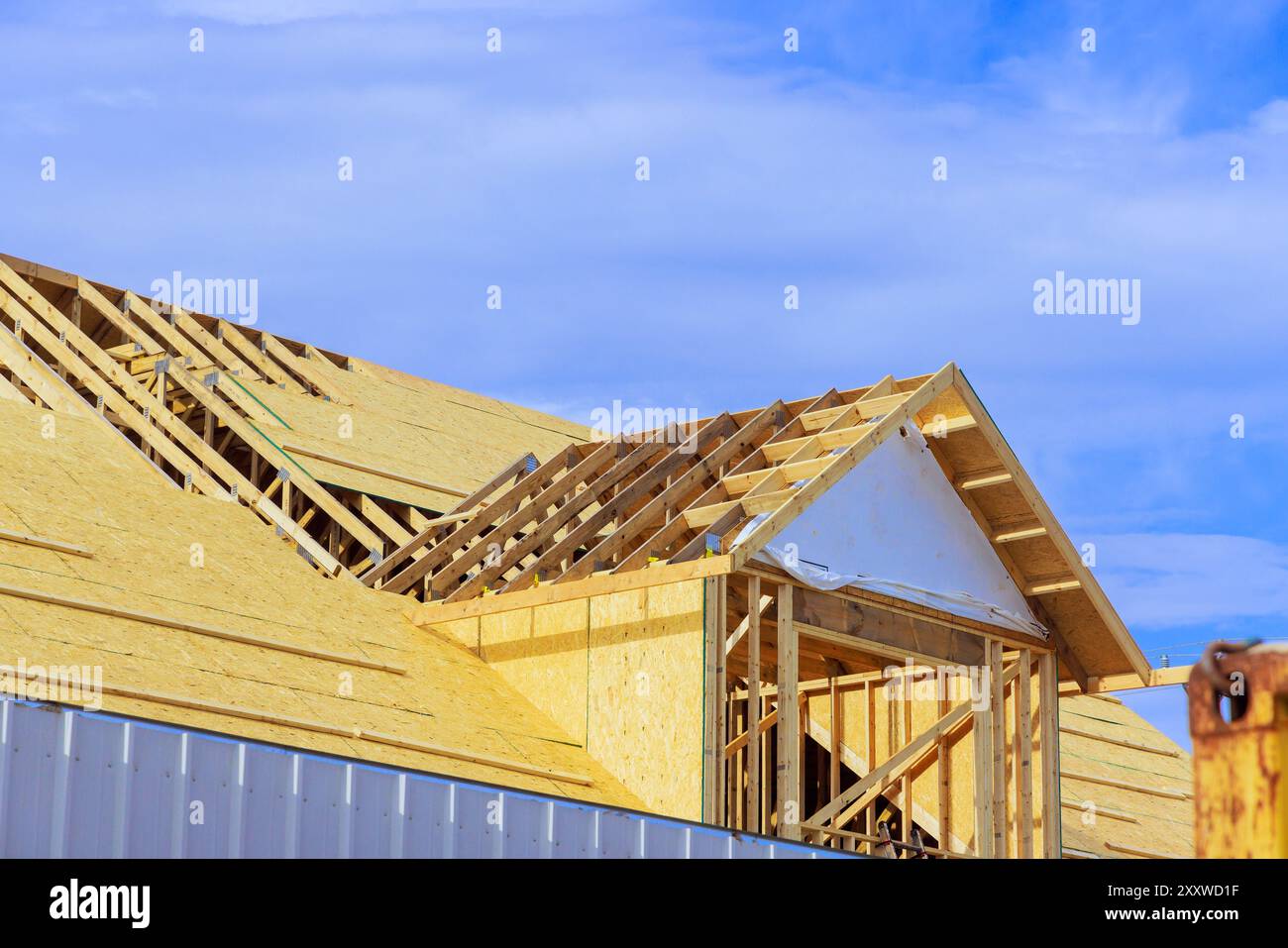 Placing plywood on wooden roofing trusses at assembled roof of house in ...