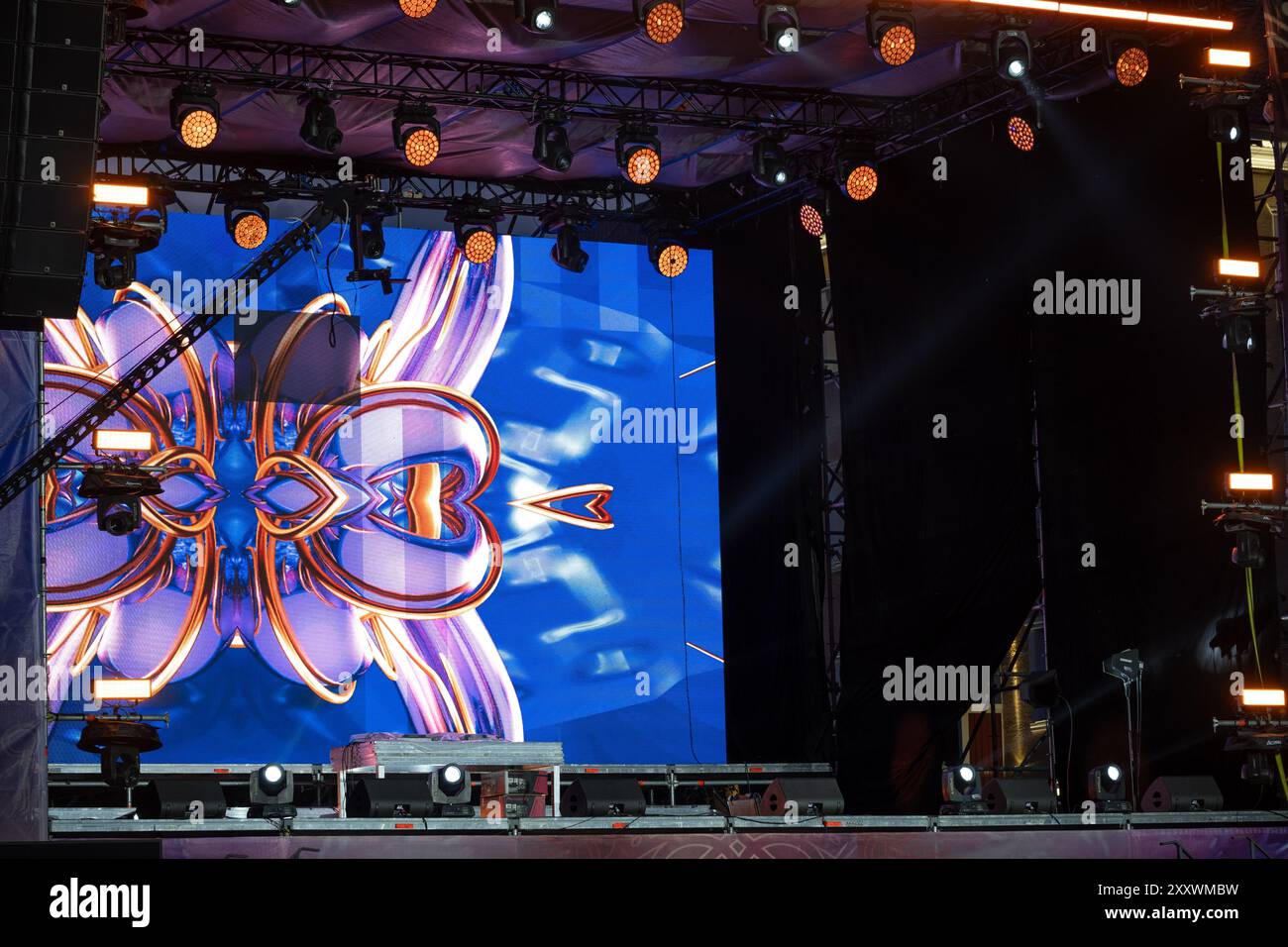 Stage with bright LED screen showing complex abstract visualizations ...