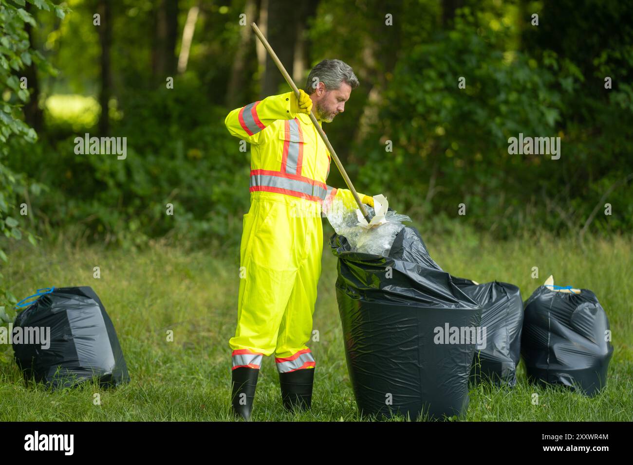 Man in uniform picking up garbage plastic for cleaning. Man collecting ...
