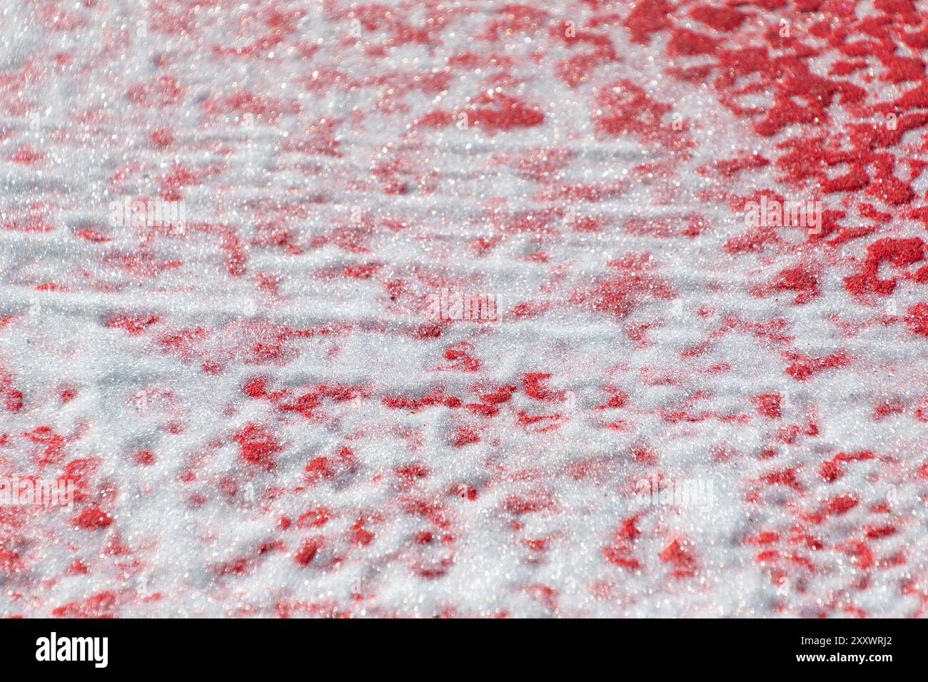 Reflective glitter on asphalt at a pedestrian crossing. Red and white ...