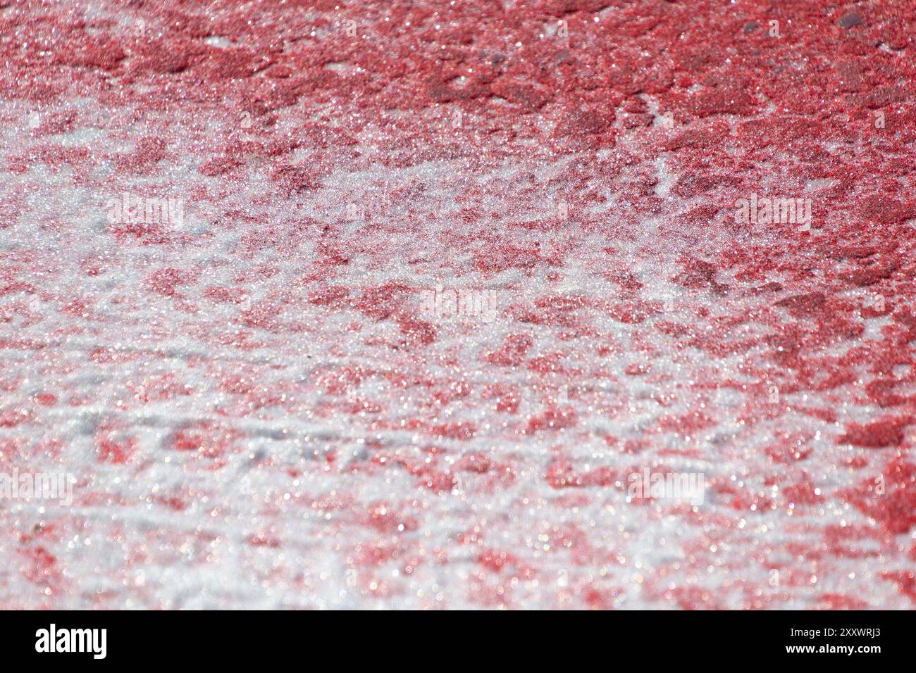 Reflective glitter on asphalt at a pedestrian crossing. Red and white ...