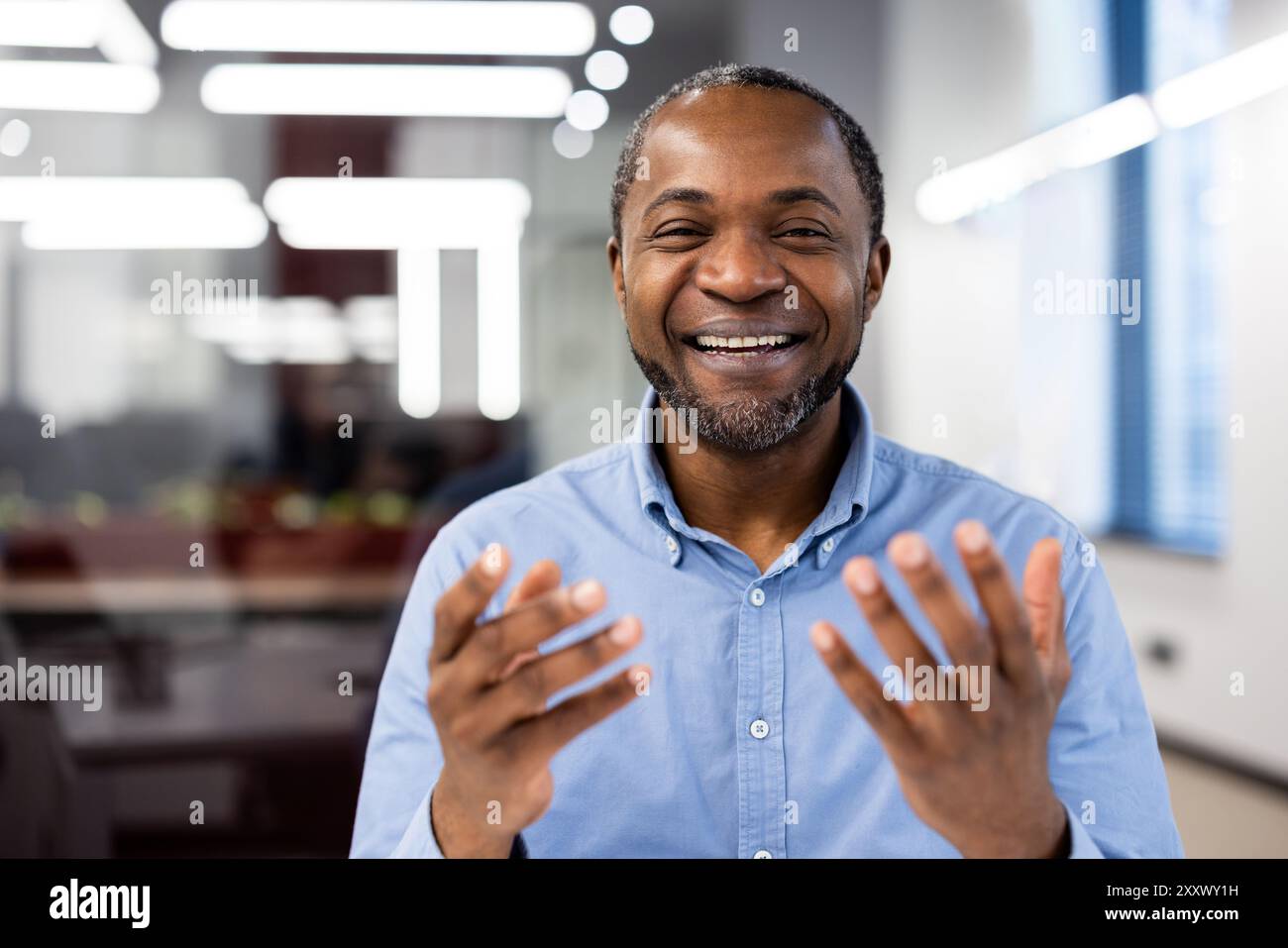 Joyful man smiling broadly in office environment, showcasing positivity ...