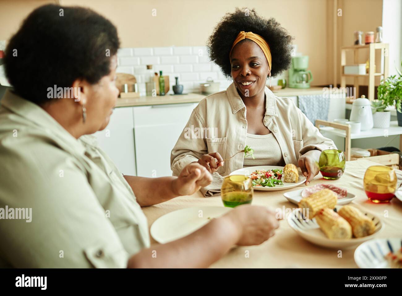 Medium shot of young smiling Black woman talking to mother while ...
