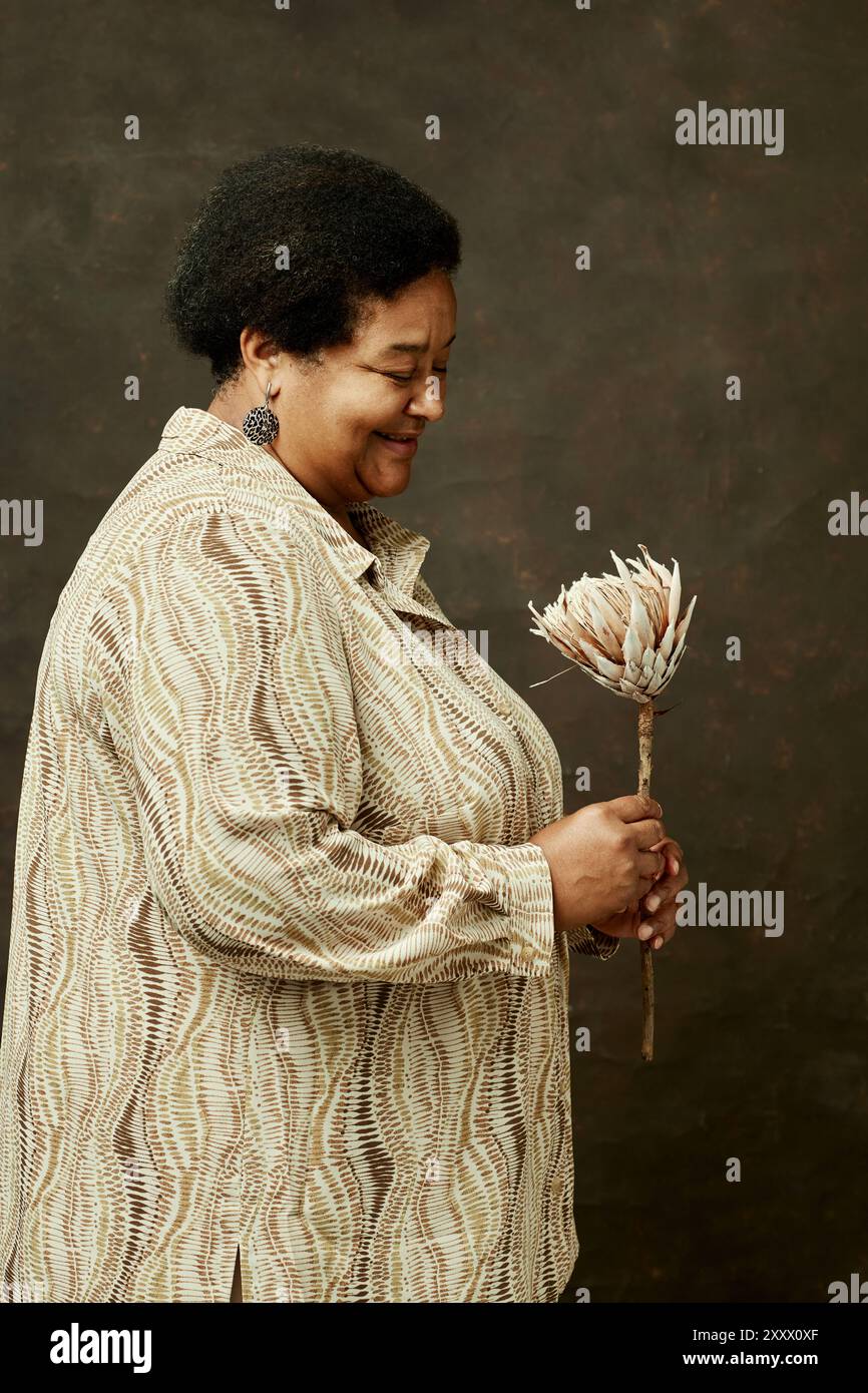 Side view of smiling elderly Black woman gently holding preserved king ...