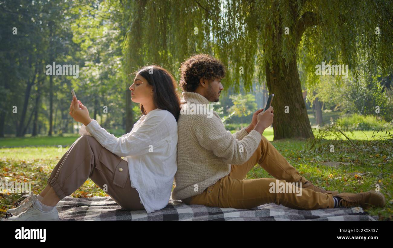 Bored Hispanic woman girlfriend Indian Arabian man boyfriend in park ...