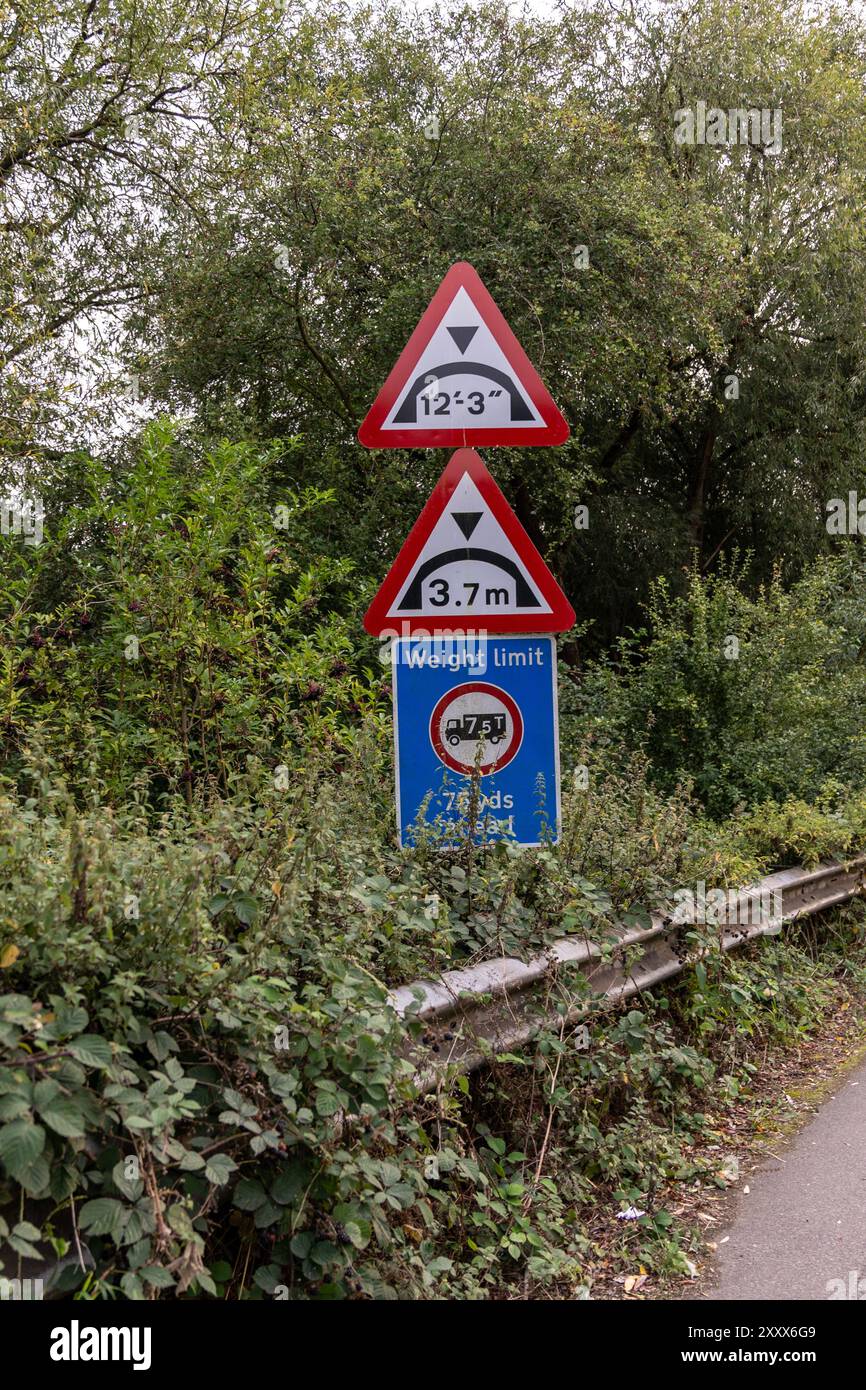 Red and white triangular road signs indicating a low bridge height and ...