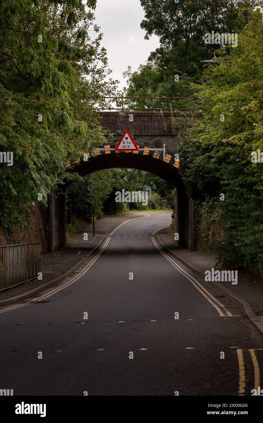 Low bridge with height warning sign and a view of the empty road beyond ...