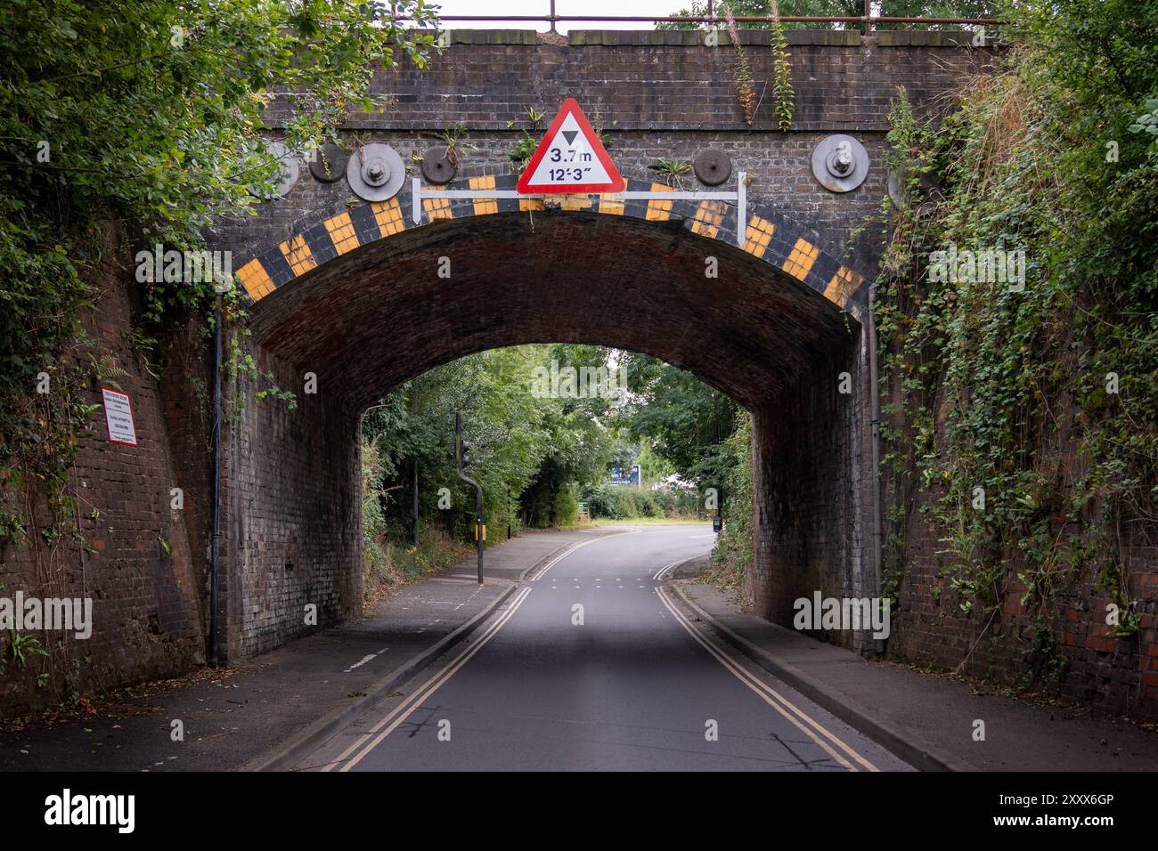 Low brick railway bridge crossing over a narrow road with a height ...