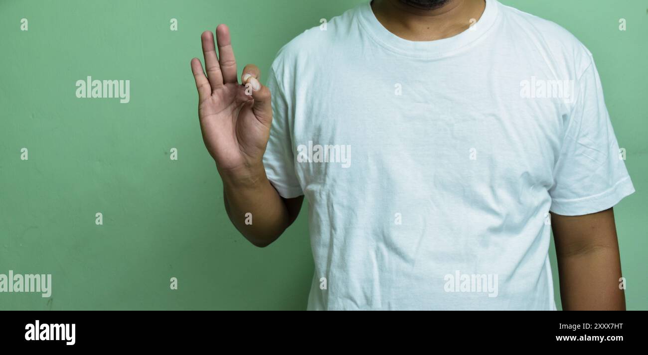 young man keeping raised while showing letter F with deaf alphabet ...