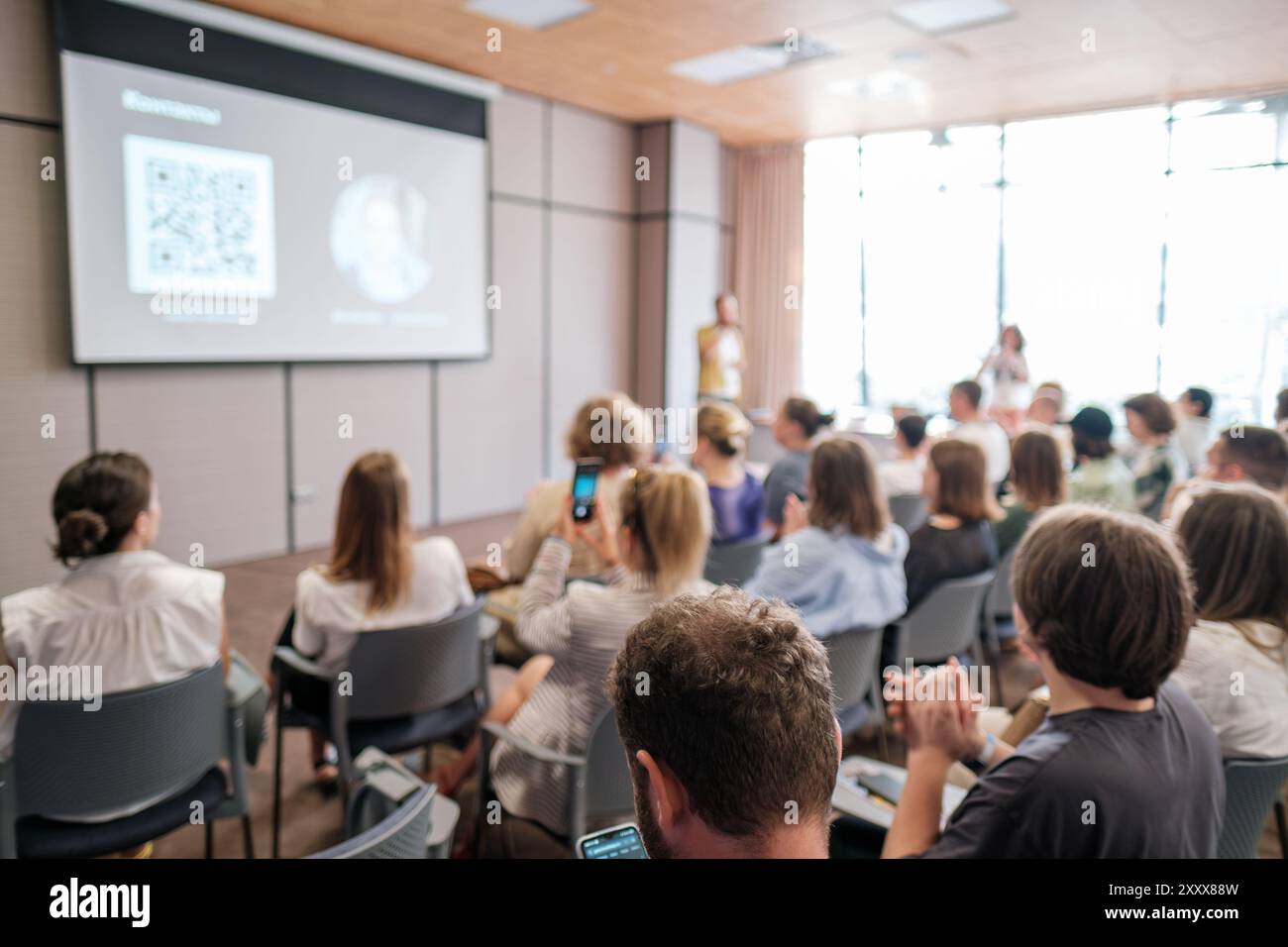 Audience attending business presentation in modern conference room ...