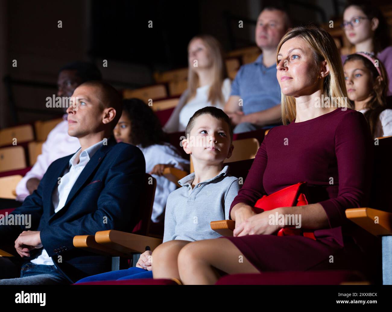 Teenage son watches spectacle with his parents in theater Stock Photo ...