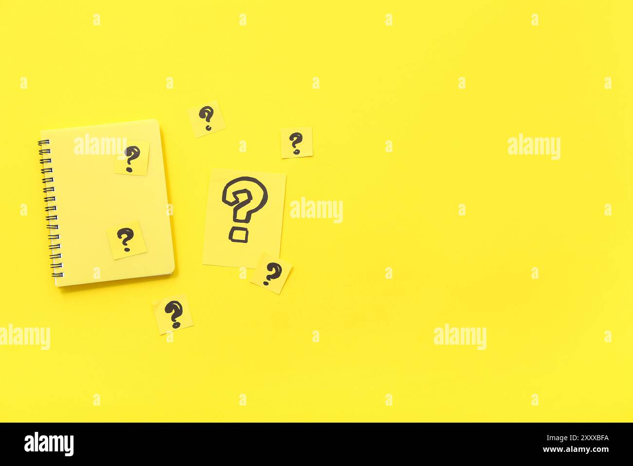 Notebook with paper question marks on yellow background Stock Photo - Alamy