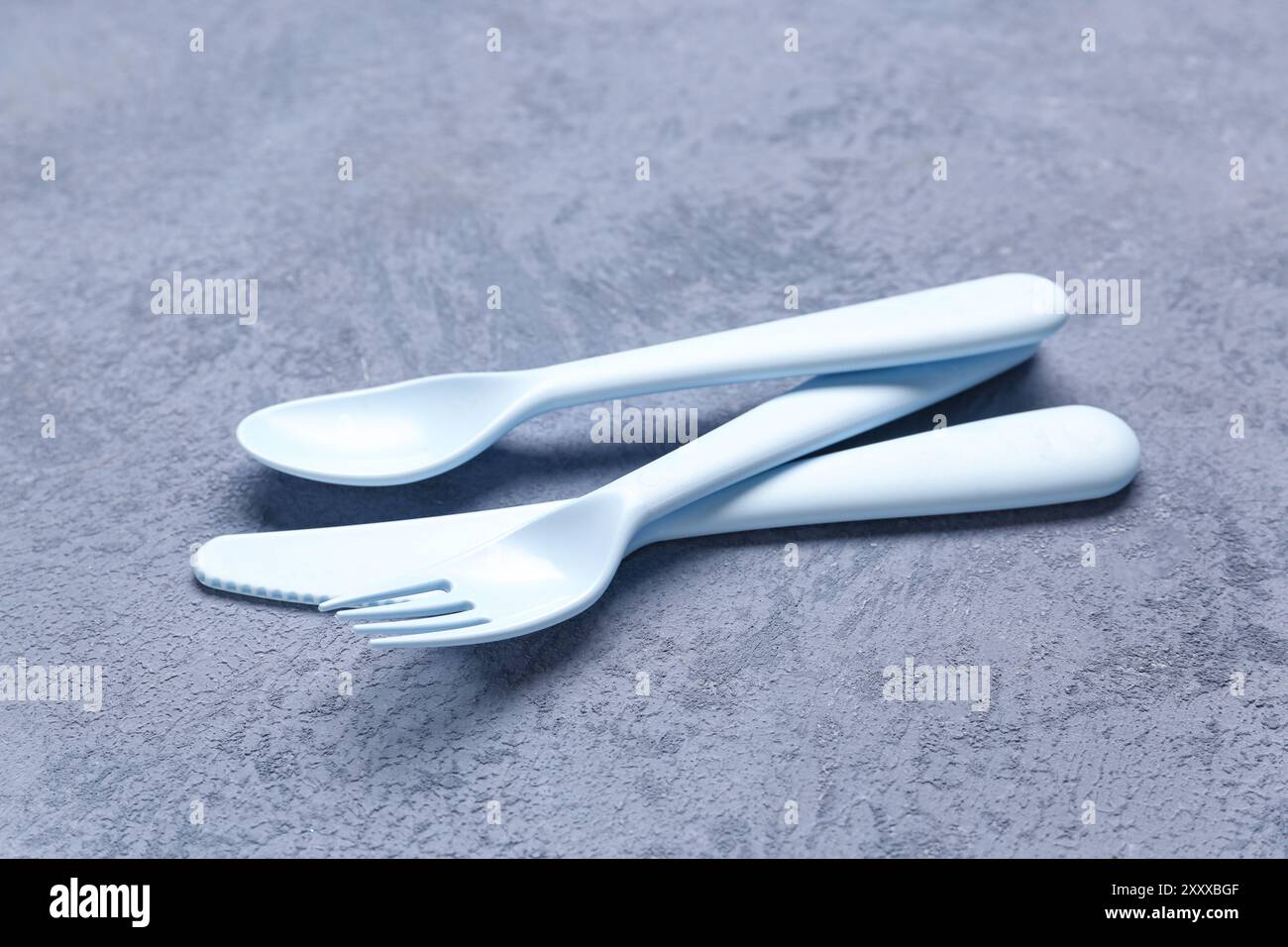 Plastic eating utensils for baby on grunge blue background Stock Photo ...
