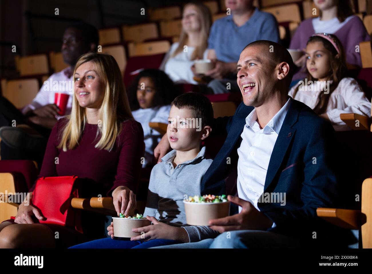 Cheerful parents with tween children watching comedy in cinema Stock ...