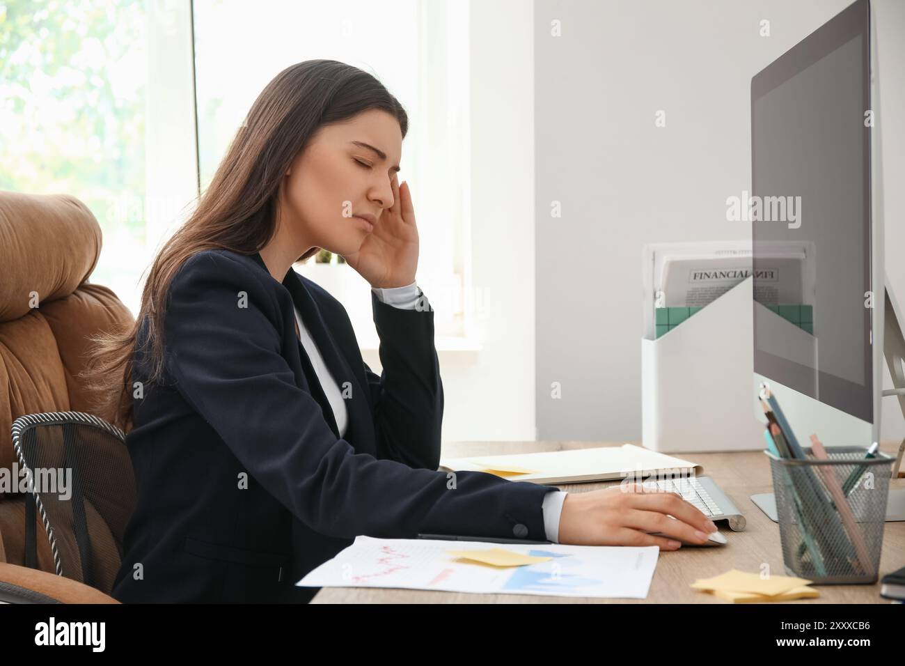 Young woman suffering from headache while working with modern computer ...