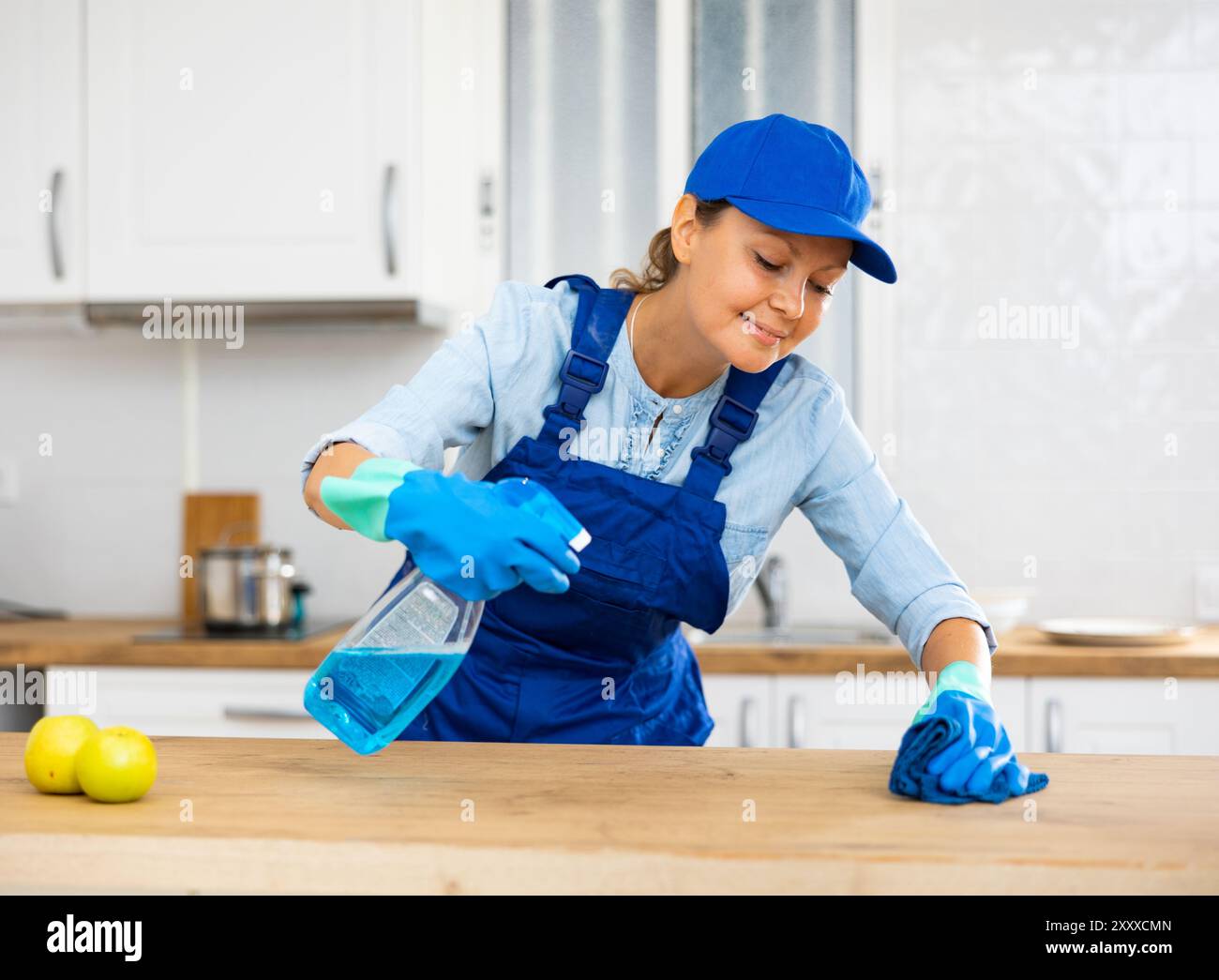 Skilled woman house cleaner sanitizing kitchen countertop Stock Photo ...