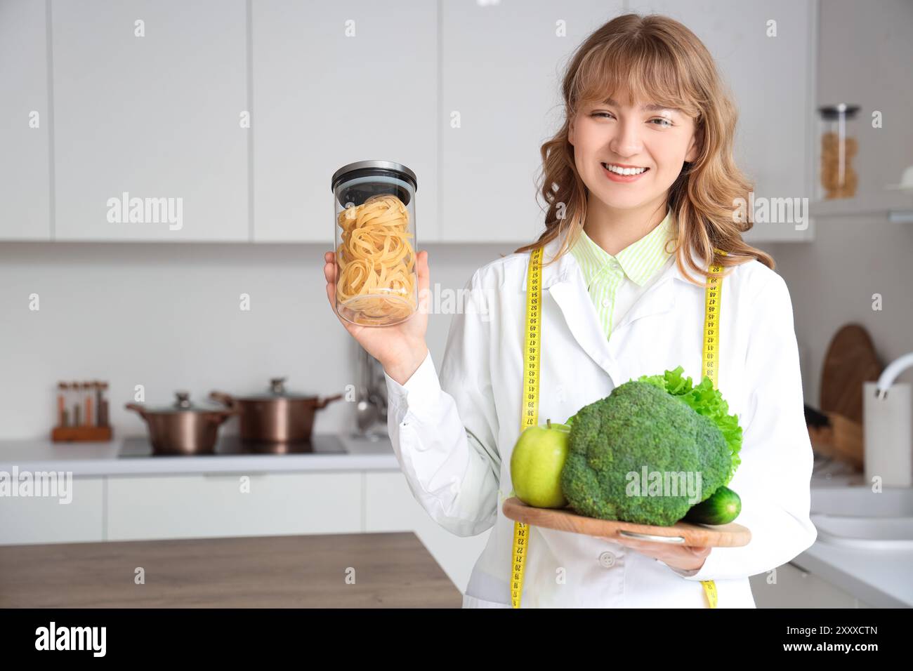 Female nutritionist with healthy food in kitchen Stock Photo - Alamy