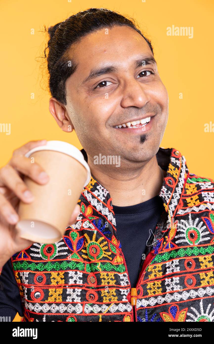 Portrait of ecstatic man wearing traditional indian clothes sipping ...
